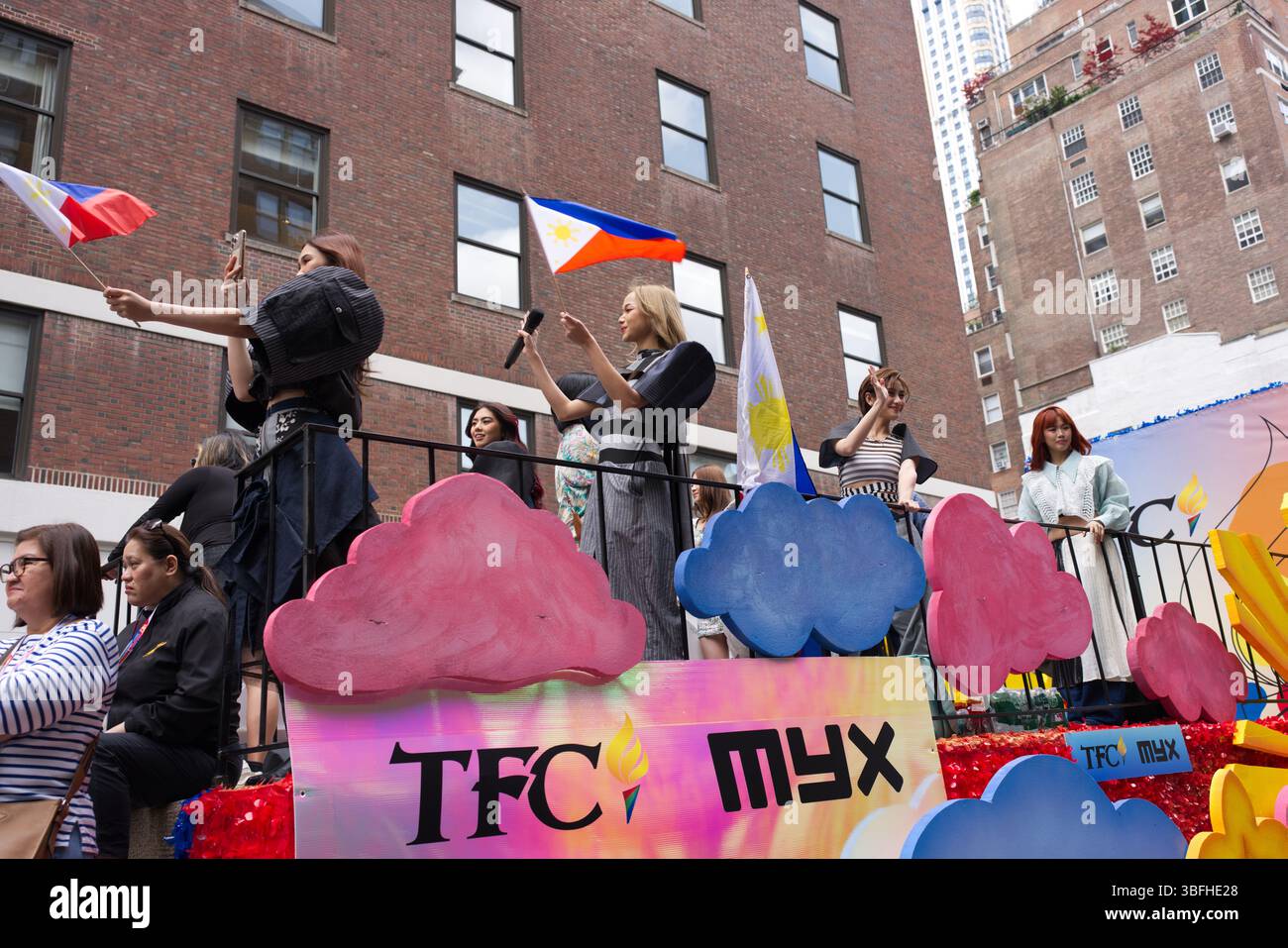 A parade float features several women, Philippine flags, and large ...