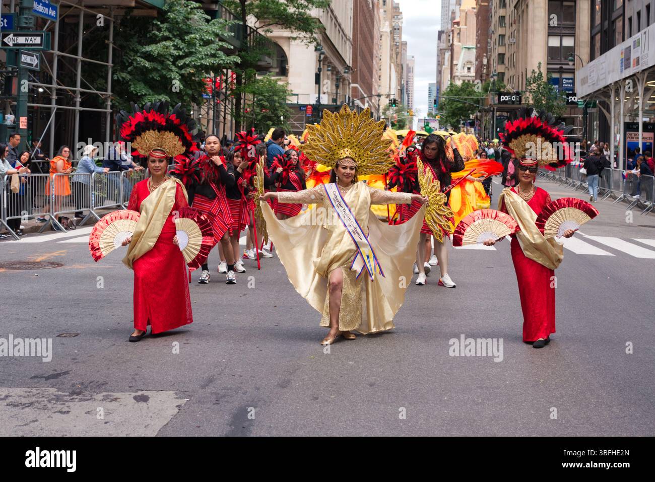 A parade featuring women in vibrant red and gold costumes, elaborate ...