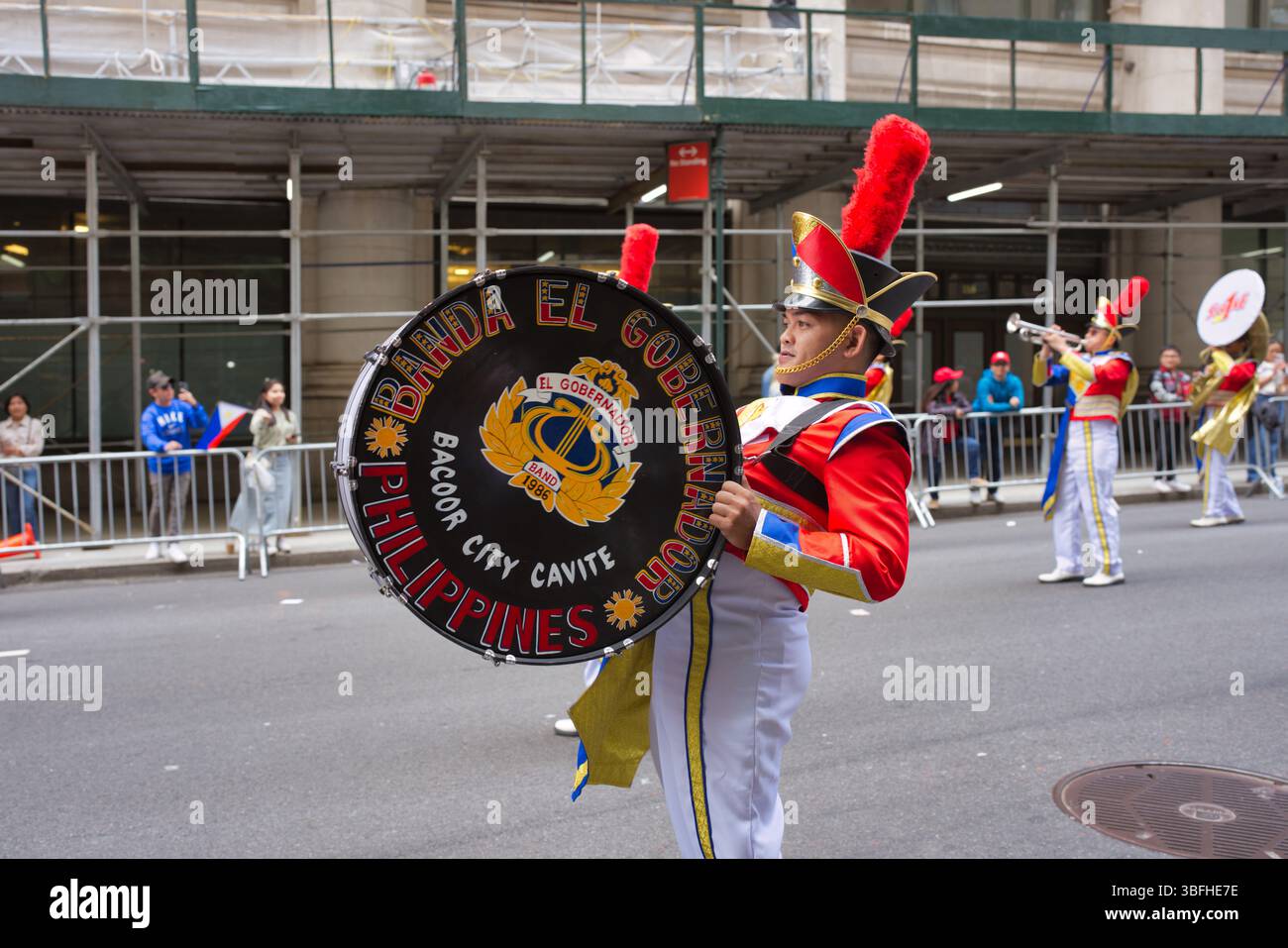 A marching band member in a red and white uniform holds a large bass ...