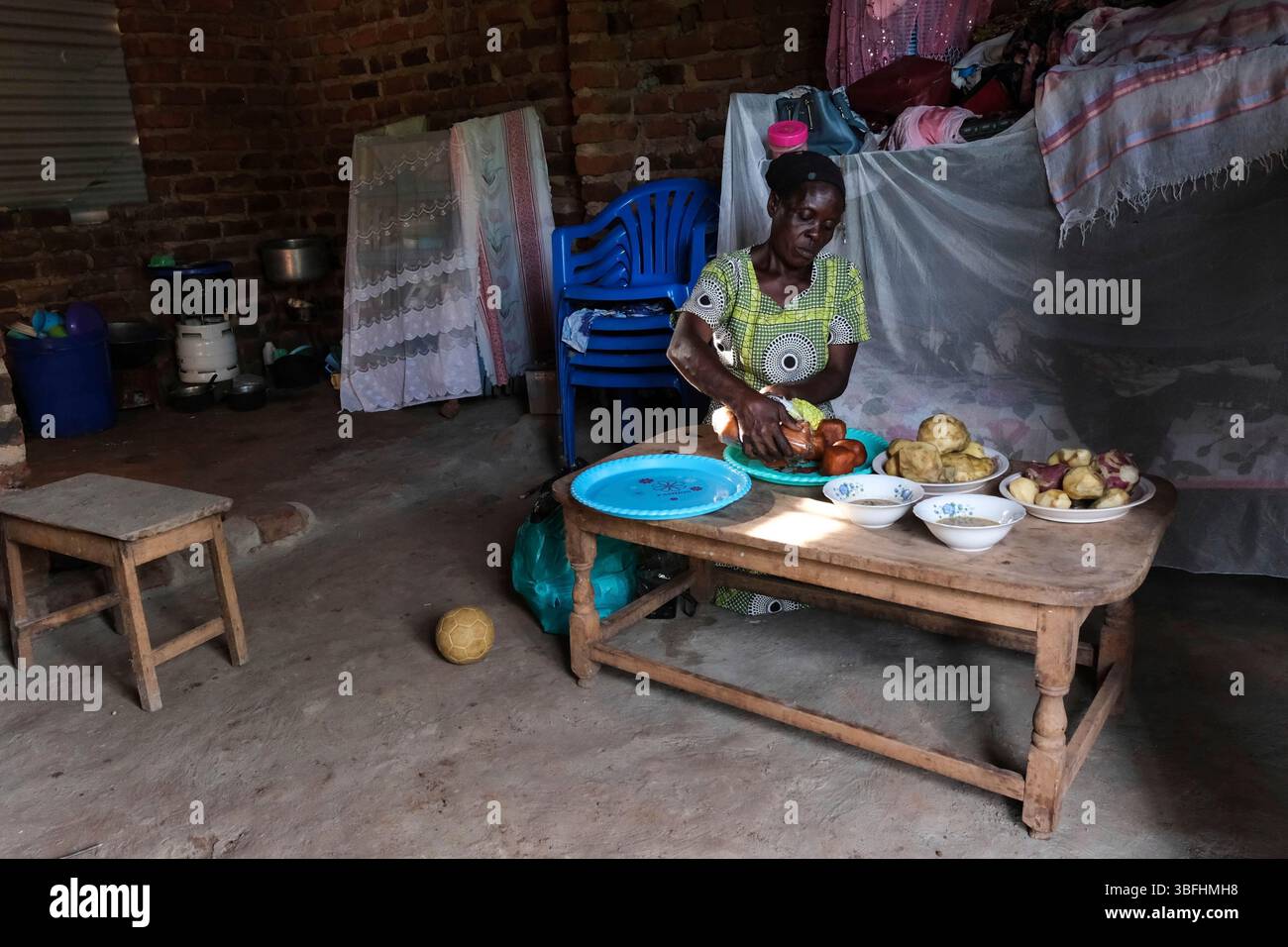 Rehema Namukose prepares a meal inside her home with clay-based earthen floors installed by ...