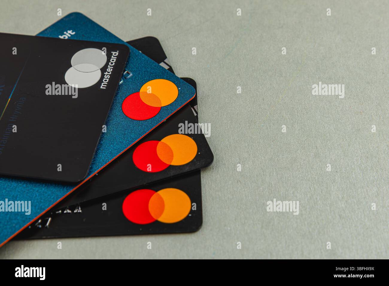 Several credit cards are stacked neatly on a light gray surface ...