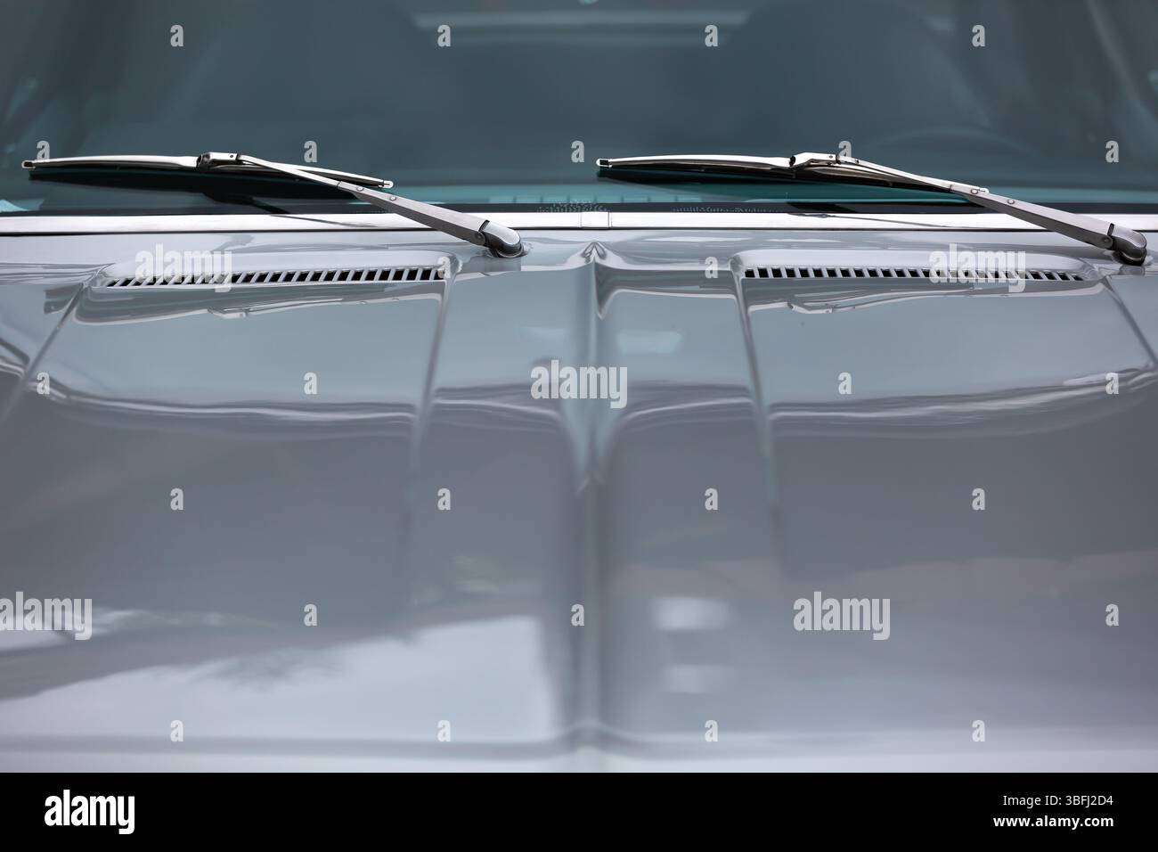 Gray bonnet, glass windshield and windshield wiper of a classic car ...