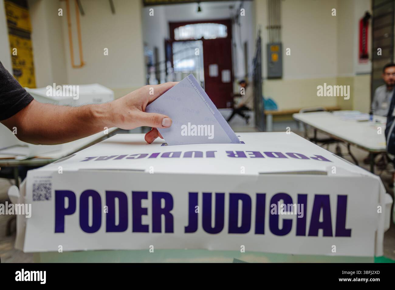 A hand places a ballot into a transparent box labeled “Poder Judicial ...