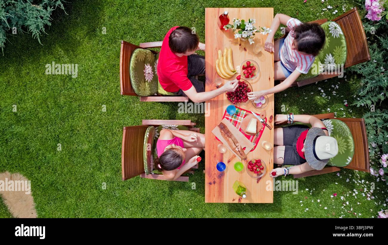 Family and friends eating together outdoors on summer garden party in ...