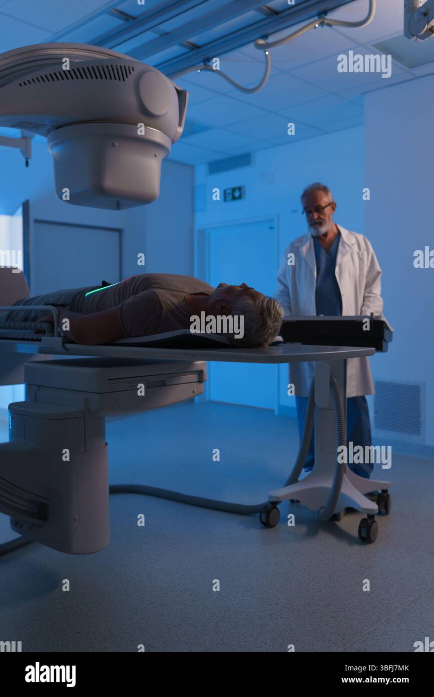 Male patient undergoing X-ray examination using tilting radiographic ...
