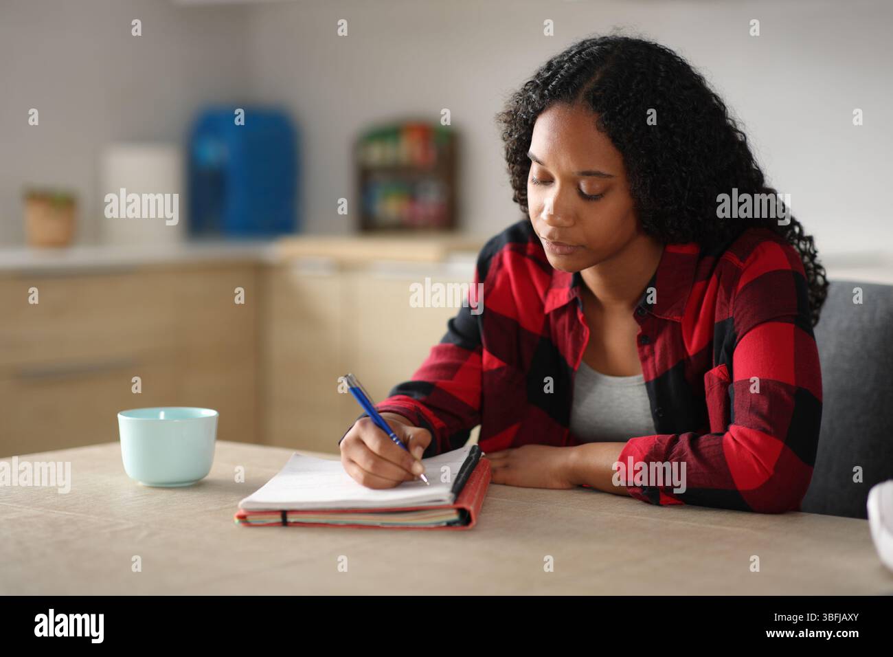 Concentrated black student learning writing notes in the kitchen at ...
