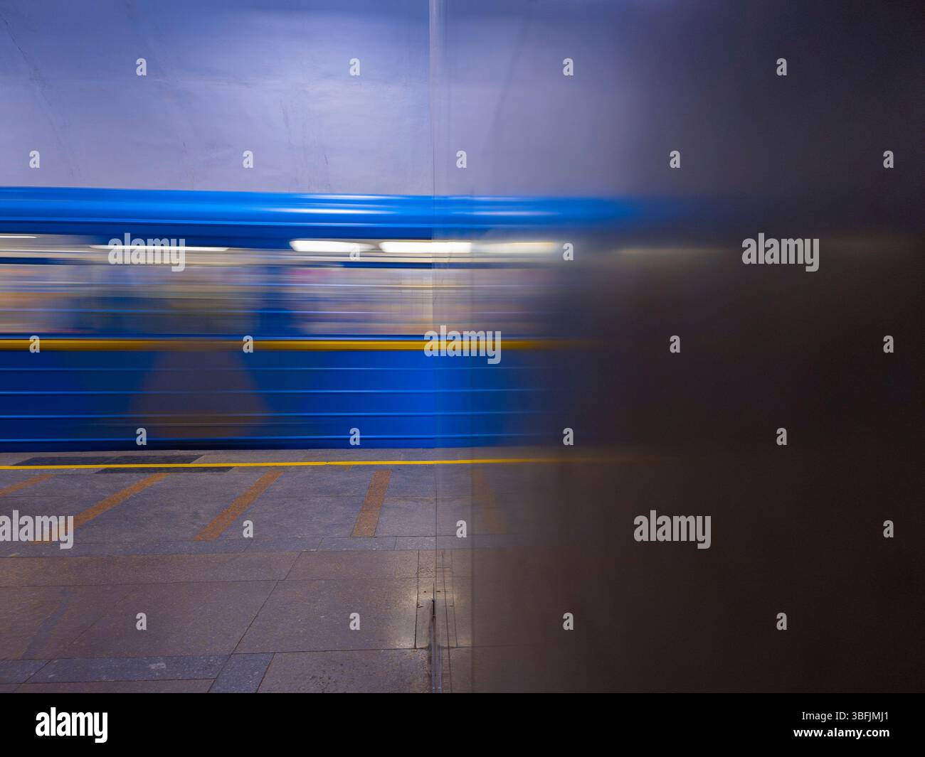 Fast-moving blue train rushing past in the subway station, creating a ...