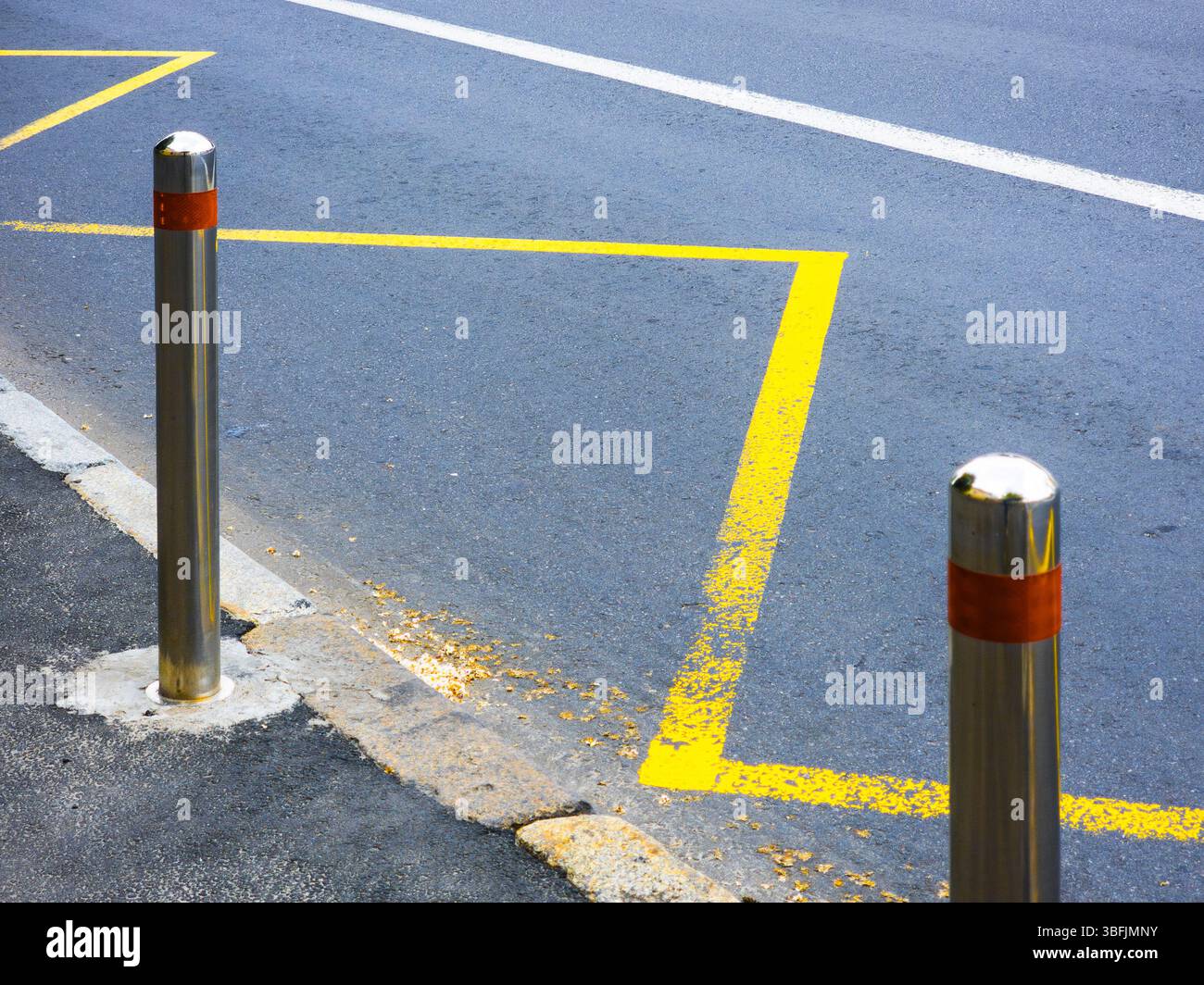 Two metallic bollards marking a reserved parking space, bordered by ...