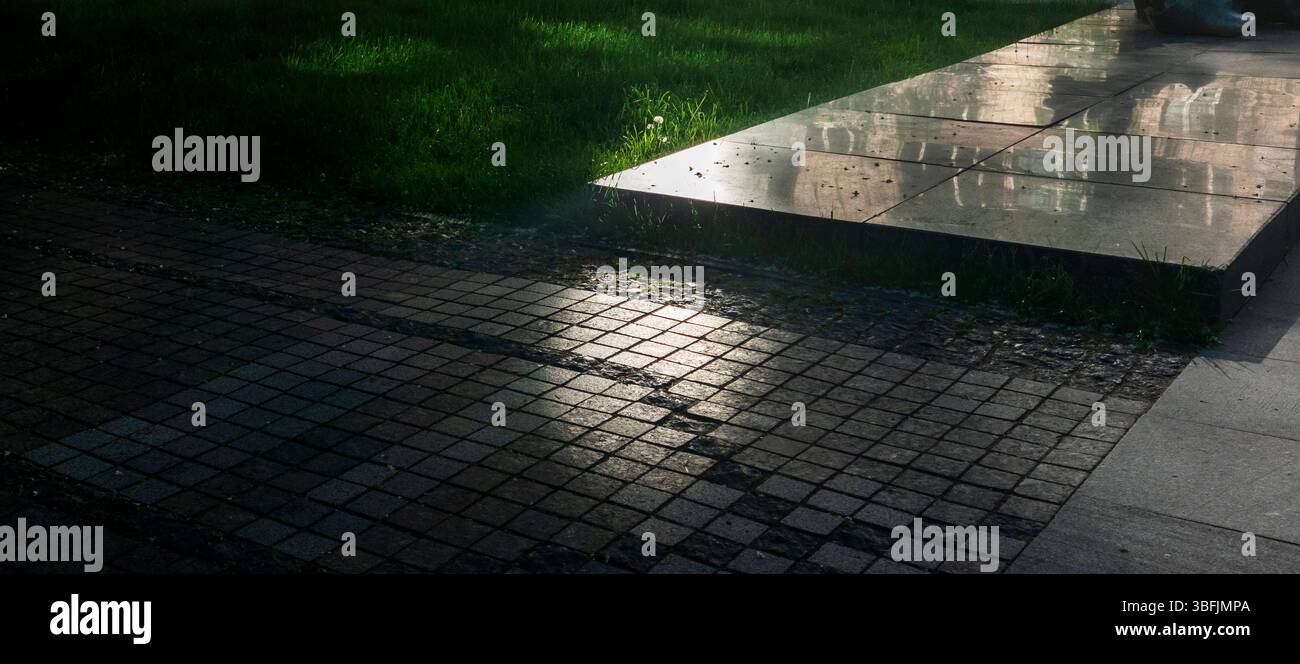 Light reflecting on wet granite tiles and illuminating cobblestone ...