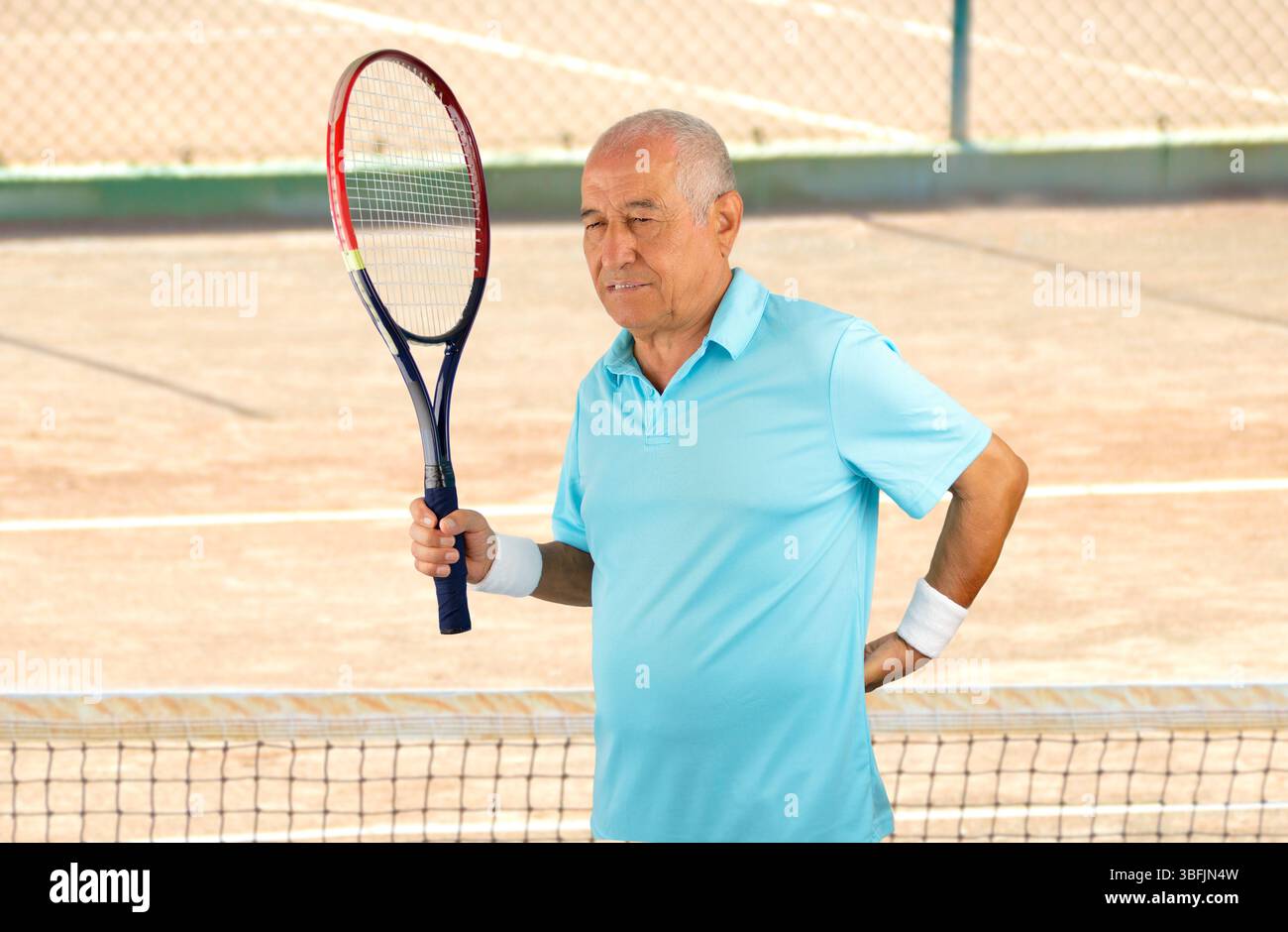 senior player tennis holding the racquet and touching his lower back in ...