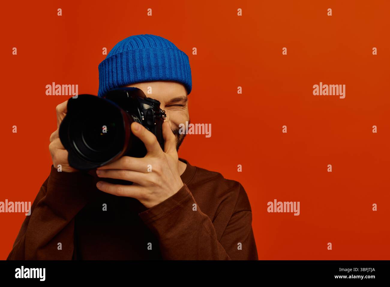 A handsome young man joyfully focuses his camera, ready to capture the ...