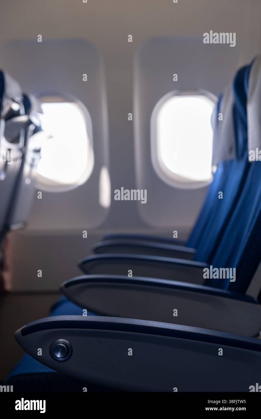 A row of airplane seats, viewed inside the cabin, with a bright window ...