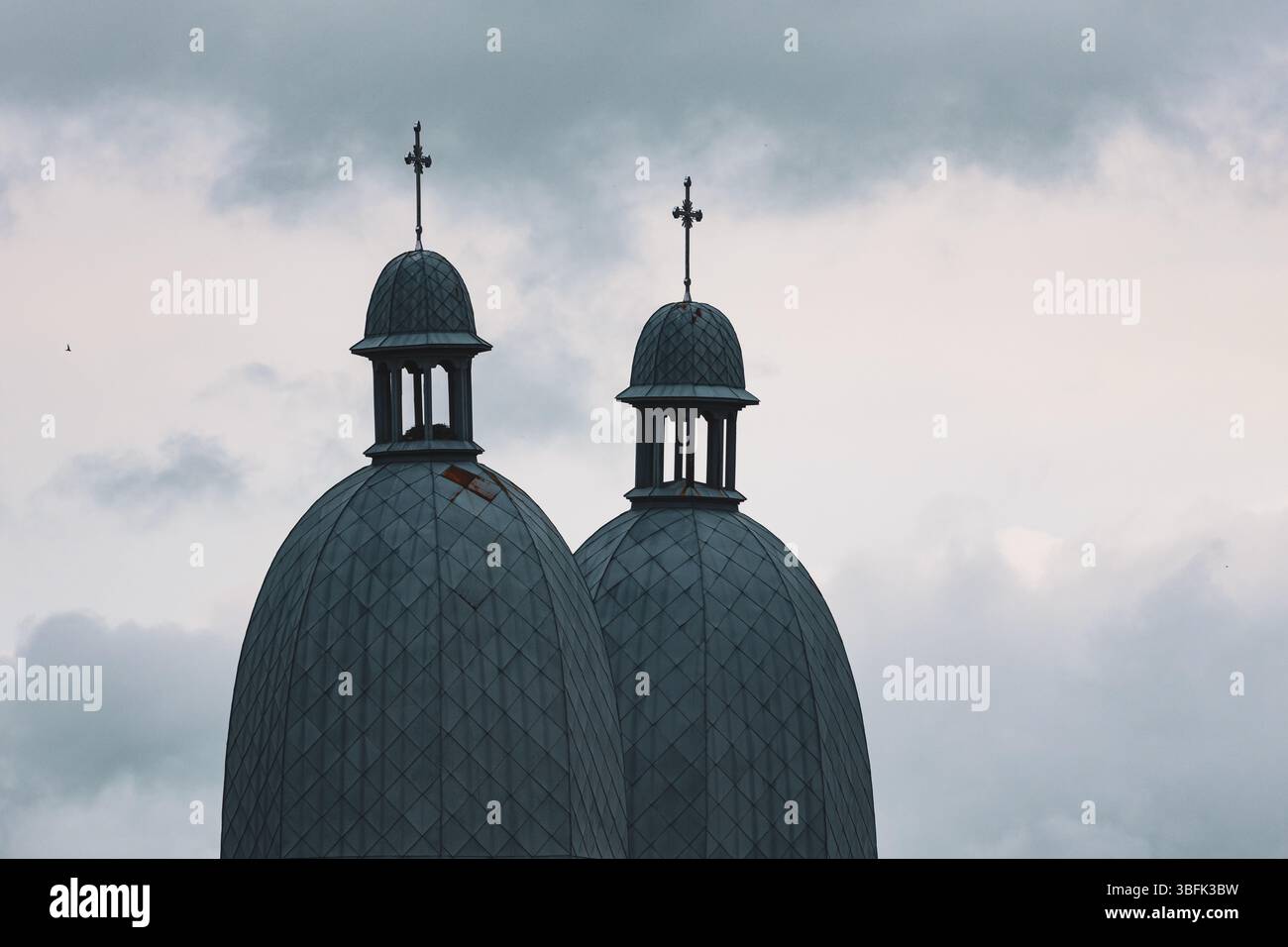 Two identical blue domes of a church tower silhouetted against a moody ...