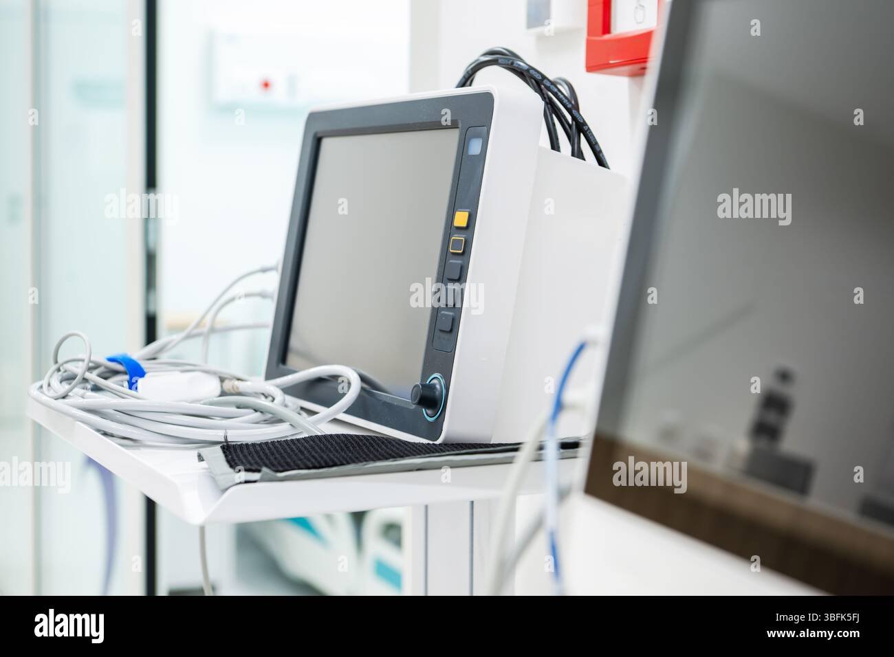 Medical monitoring equipment is set up in a hospital room. Cables and ...