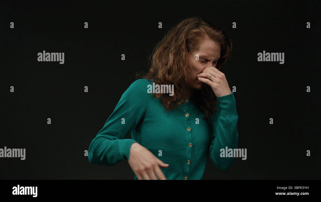 Woman expressing disgust on isolated black background, wearing a green ...