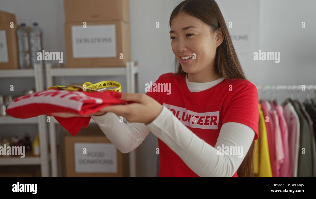 Woman wearing red volunteer shirt at donation center organizing clothes ...