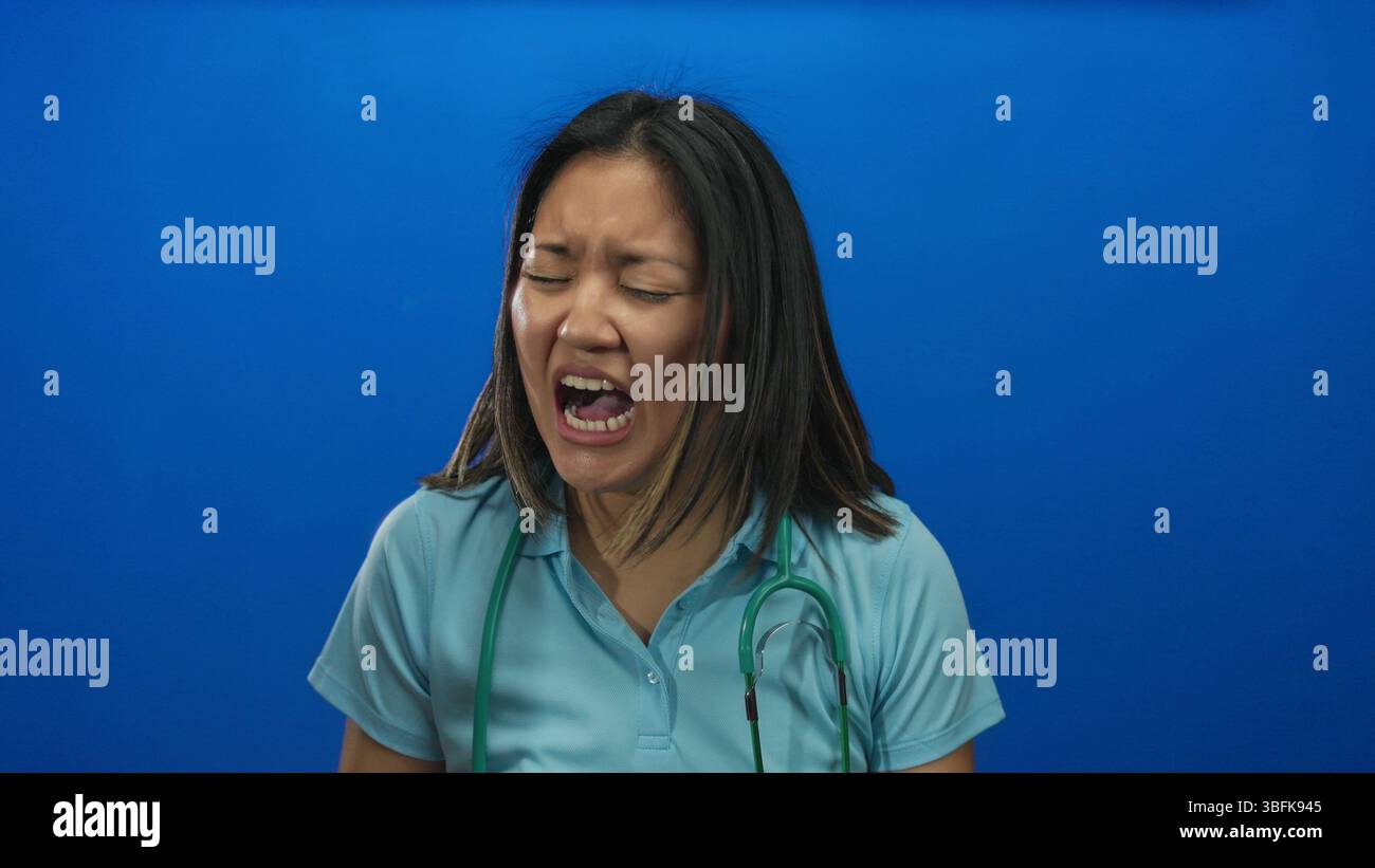 Young chinese woman doctor in distress with stethoscope over blue ...