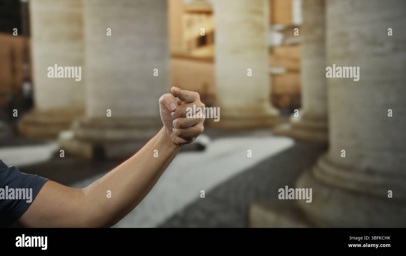 Man's hand pointing at camera outdoors with ancient university columns ...