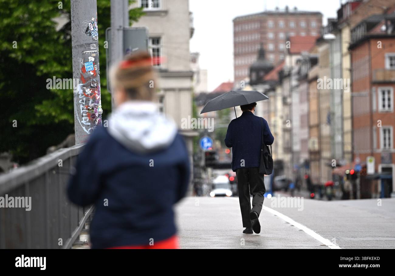 Munich, Germany. 02nd June, 2025. A man with an umbrella walks in the ...