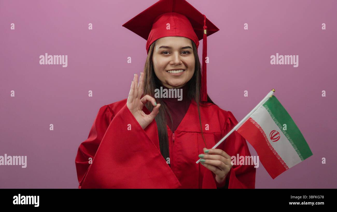 Woman in red graduation gown holding iranian flag against pink ...