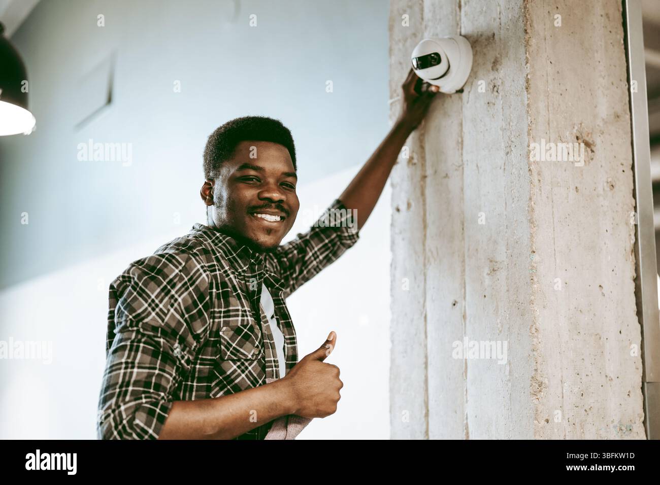 Man installing security camera in modern office space while smiling and ...