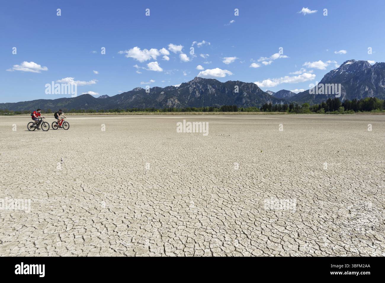 Cracked, dried out ground, waterless Forggensee in spring, behind it ...