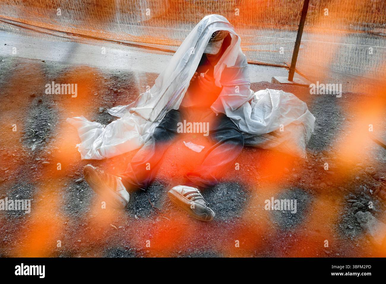 A Colombian drug user sits on the ground and smokes basuco – an ...