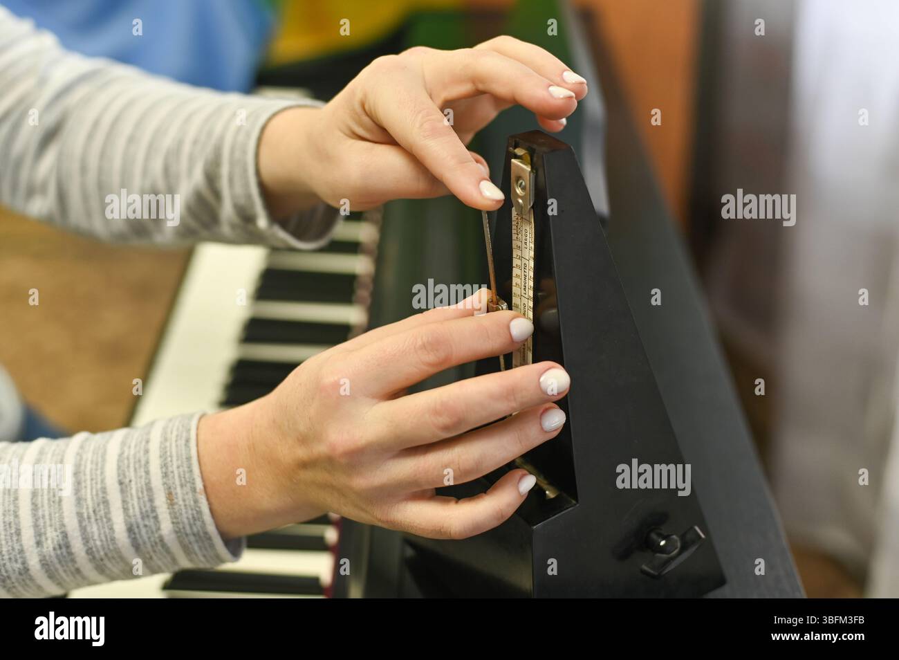 Female hands adjusting metronome on piano, focusing on music rhythm and ...
