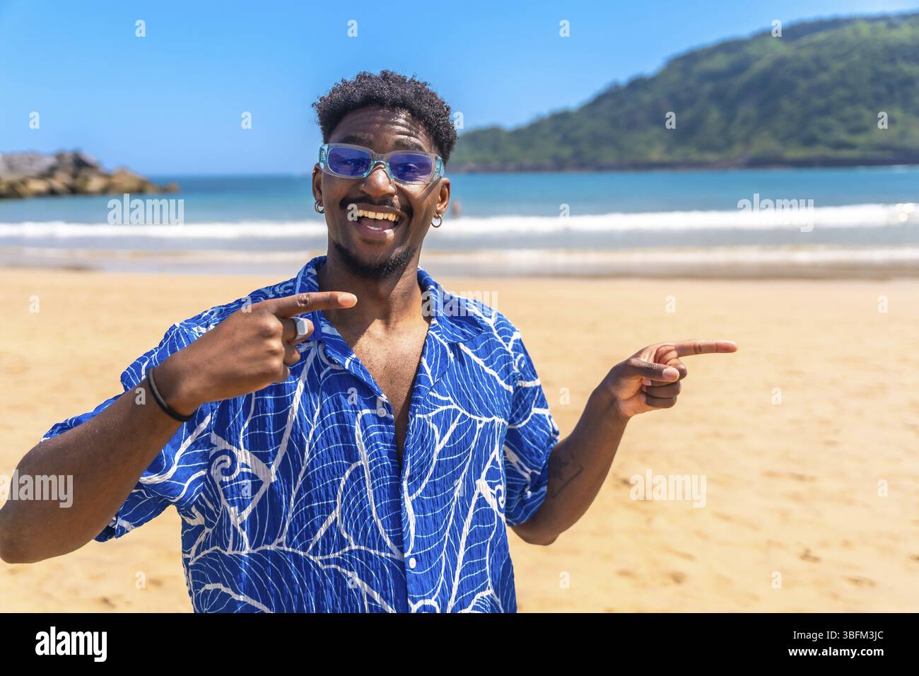 Young man pointing at himself and to the side with index fingers while ...