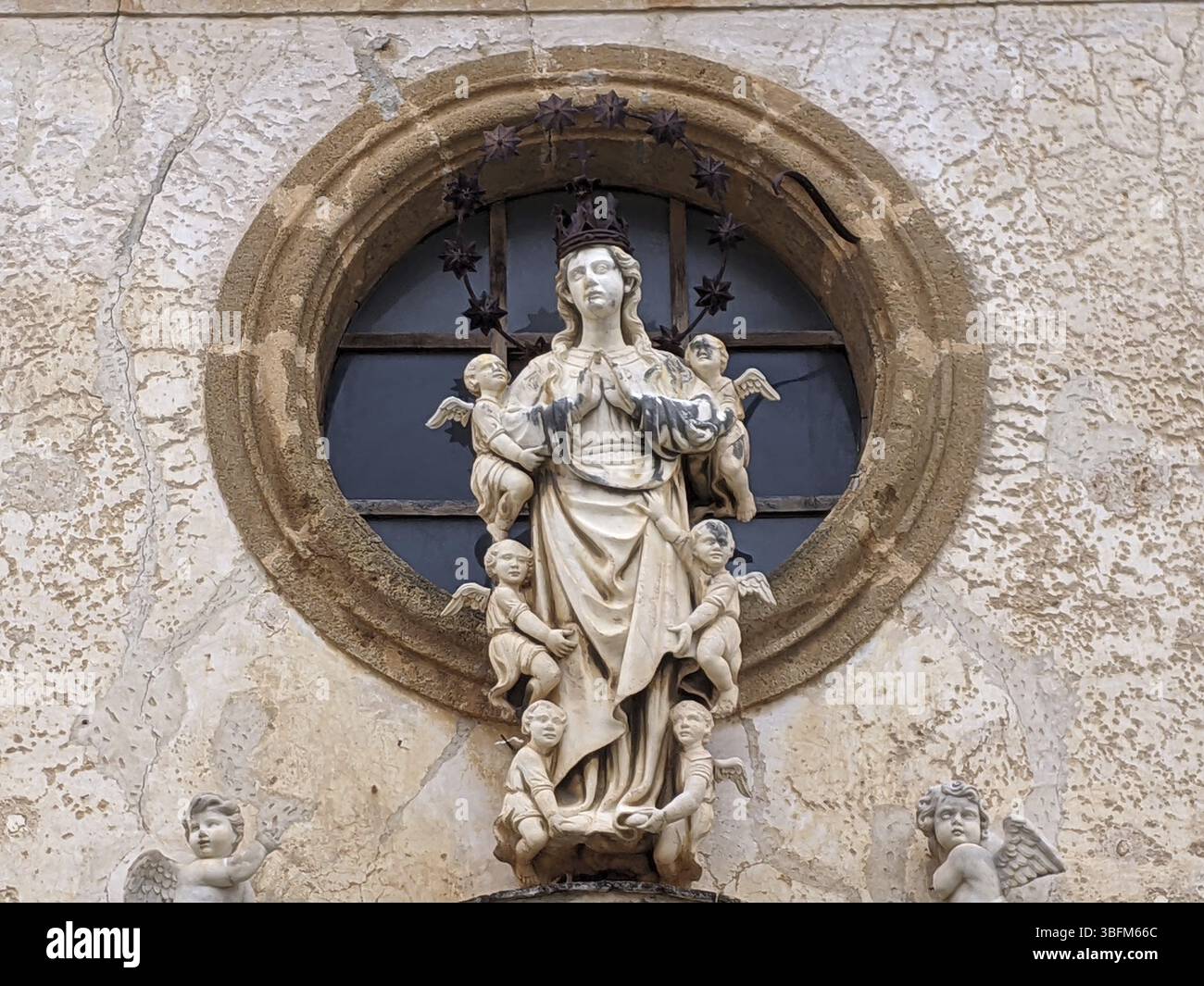 Ornate stone sculpture of the Virgin Mary with angels set around a ...
