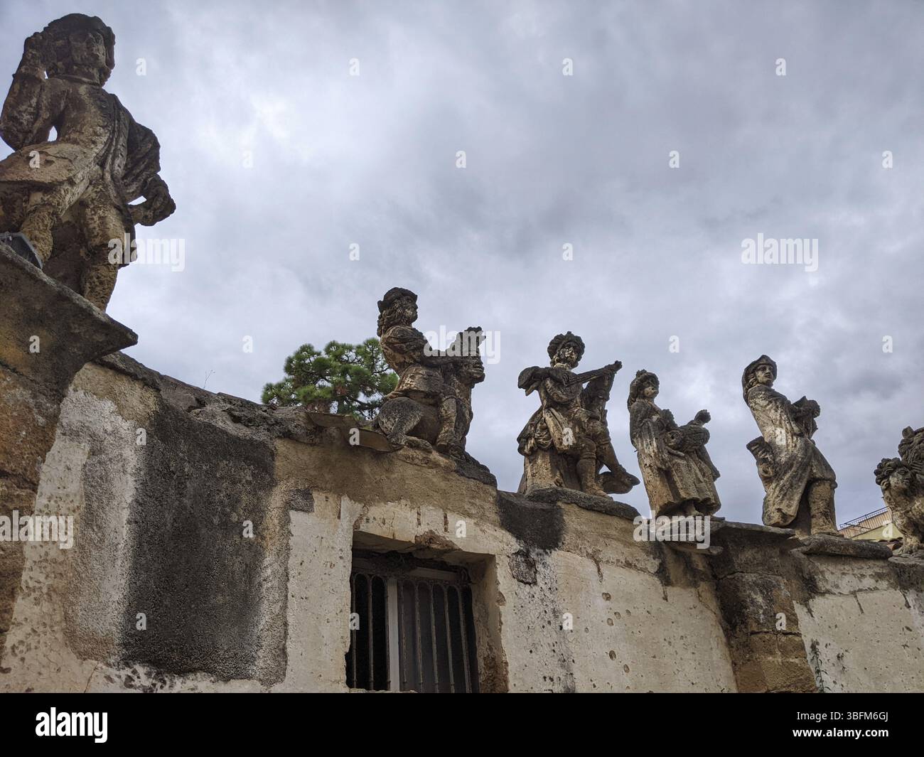 Rooftop stone statues depicting historical figures against an overcast ...
