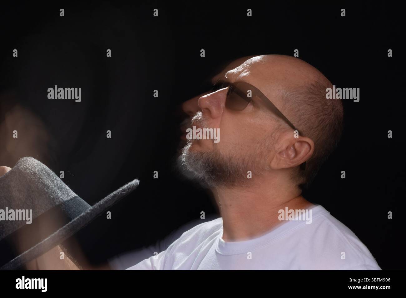 Artistic portrait of bearded bald man in white shirt making motion blur ...