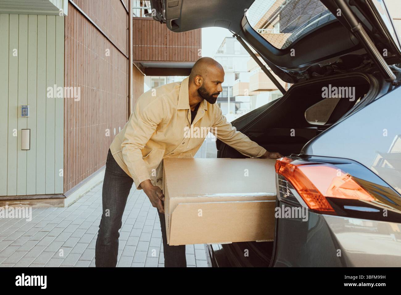 Mature man loading cardboard box in car trunk Stock Photo - Alamy