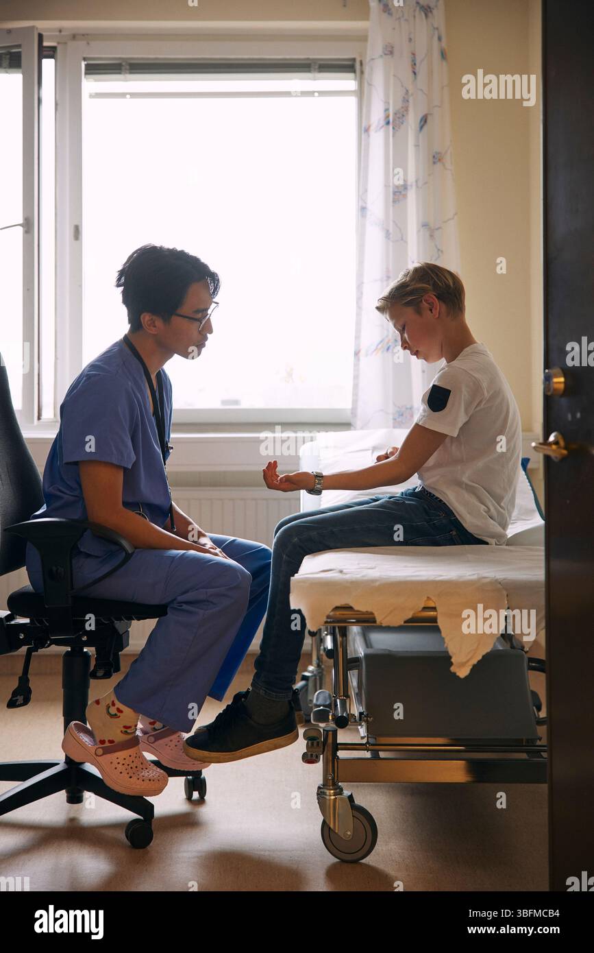 Boy discussing over arm with doctor in medical clinic Stock Photo - Alamy