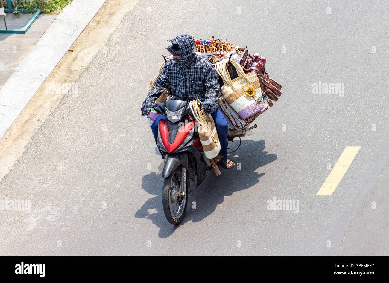 Vendor riding a motorcycle full loaded with an array of handmade bags ...