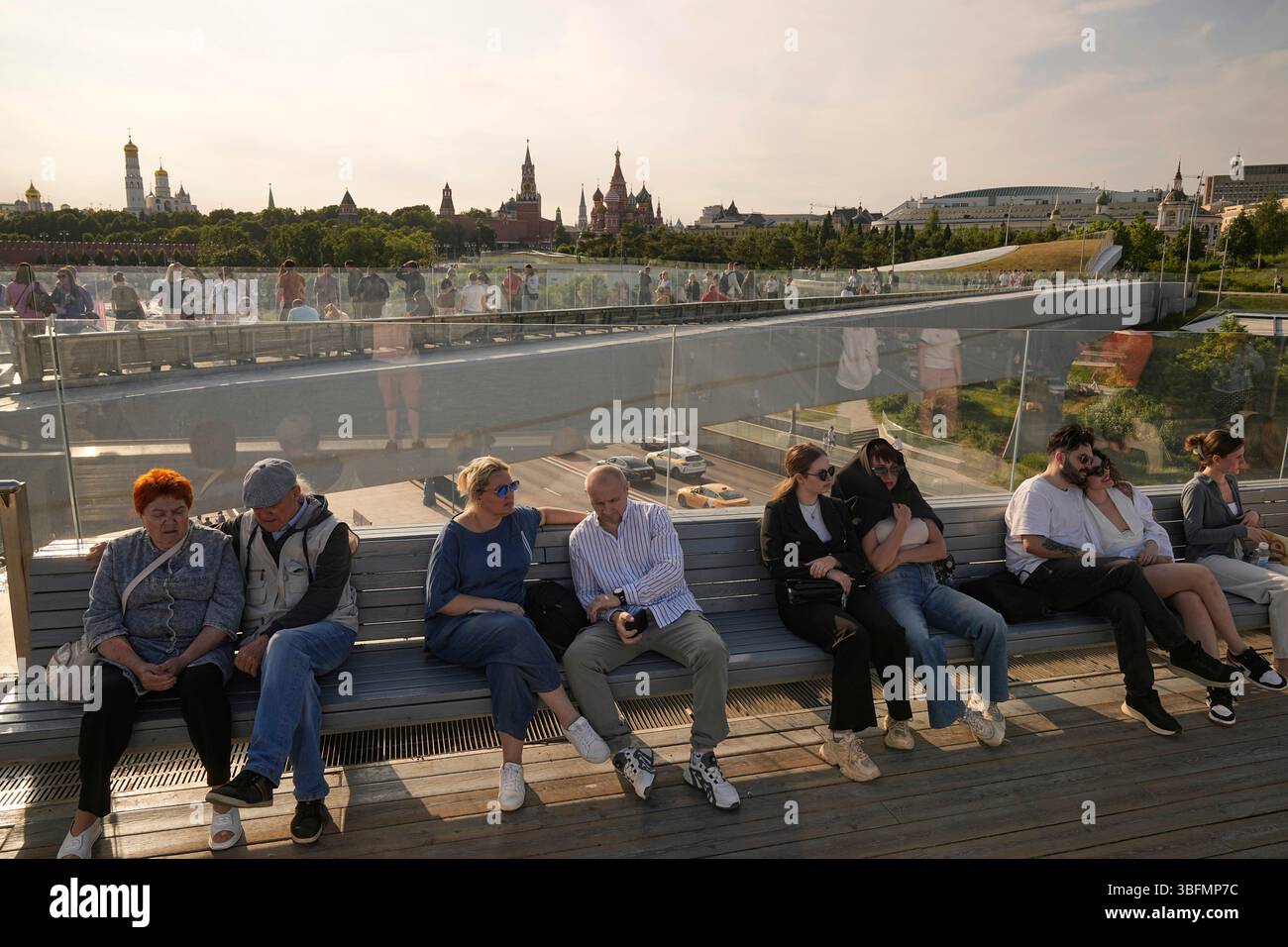 People sit near the Floating bridge at the Zaryadye park on a hot day ...