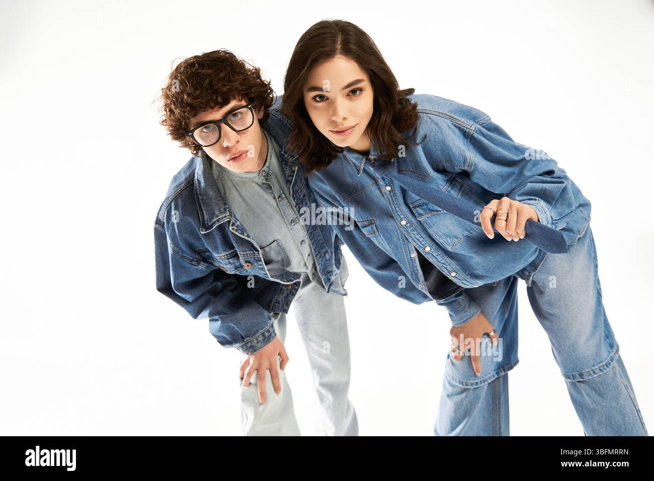 A young couple has fun modeling their trendy denim outfits in a bright ...