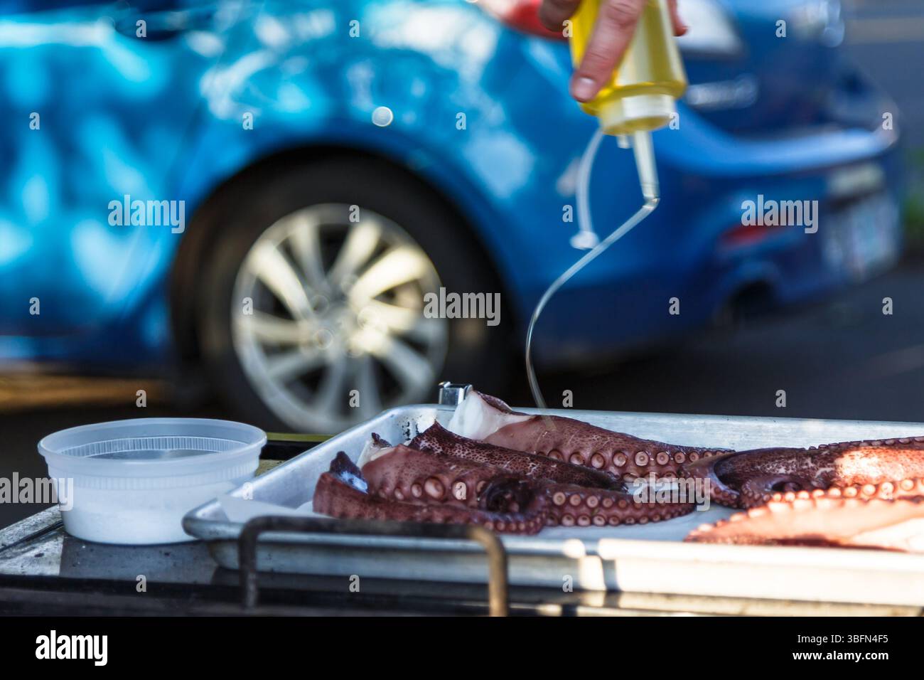 A chef prepares octopus with oil, likely for grilling, adding flavor ...
