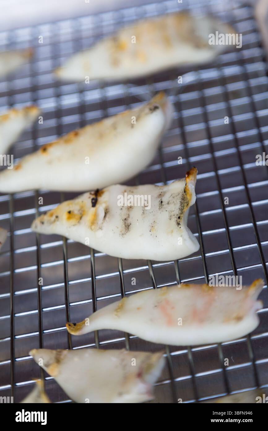 Grilled squid on a metal rack, ready to be served. The squid is lightly ...