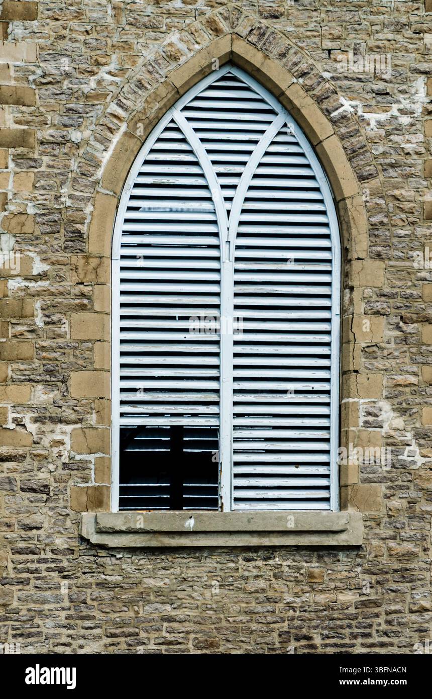 A shuttered stone church tower window with some slats broken out Stock ...