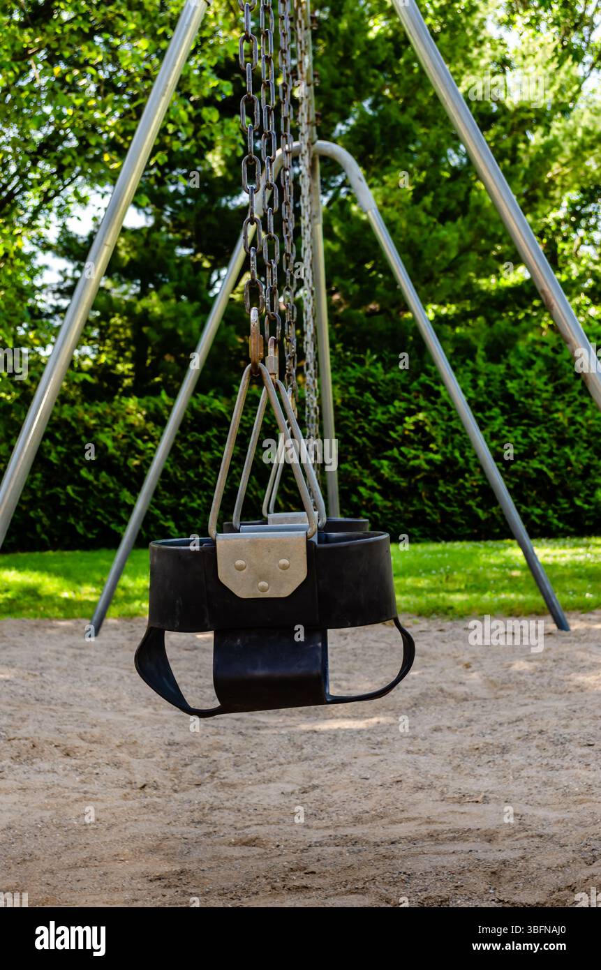 Symetrical row of child swing seats on a steel swing set in a public ...
