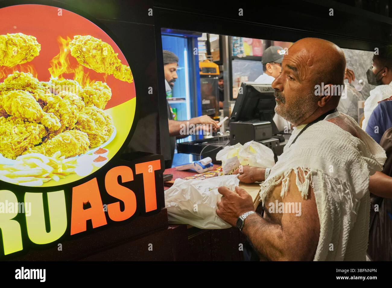 A Muslim pilgrim buys fried chicken at a shop outside the Grand Mosque ...