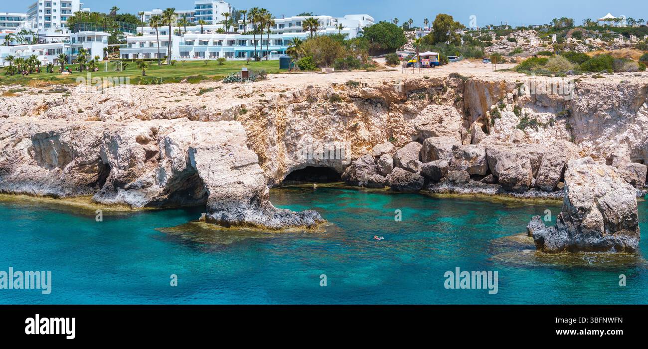 Rugged limestone cliffs with natural caves meet clear turquoise waters ...