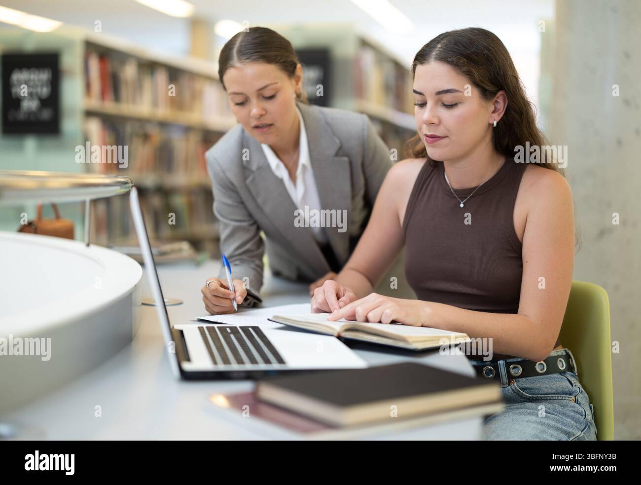 female student works at a notebook, and a fellow student helps her Stock Photo - Alamy