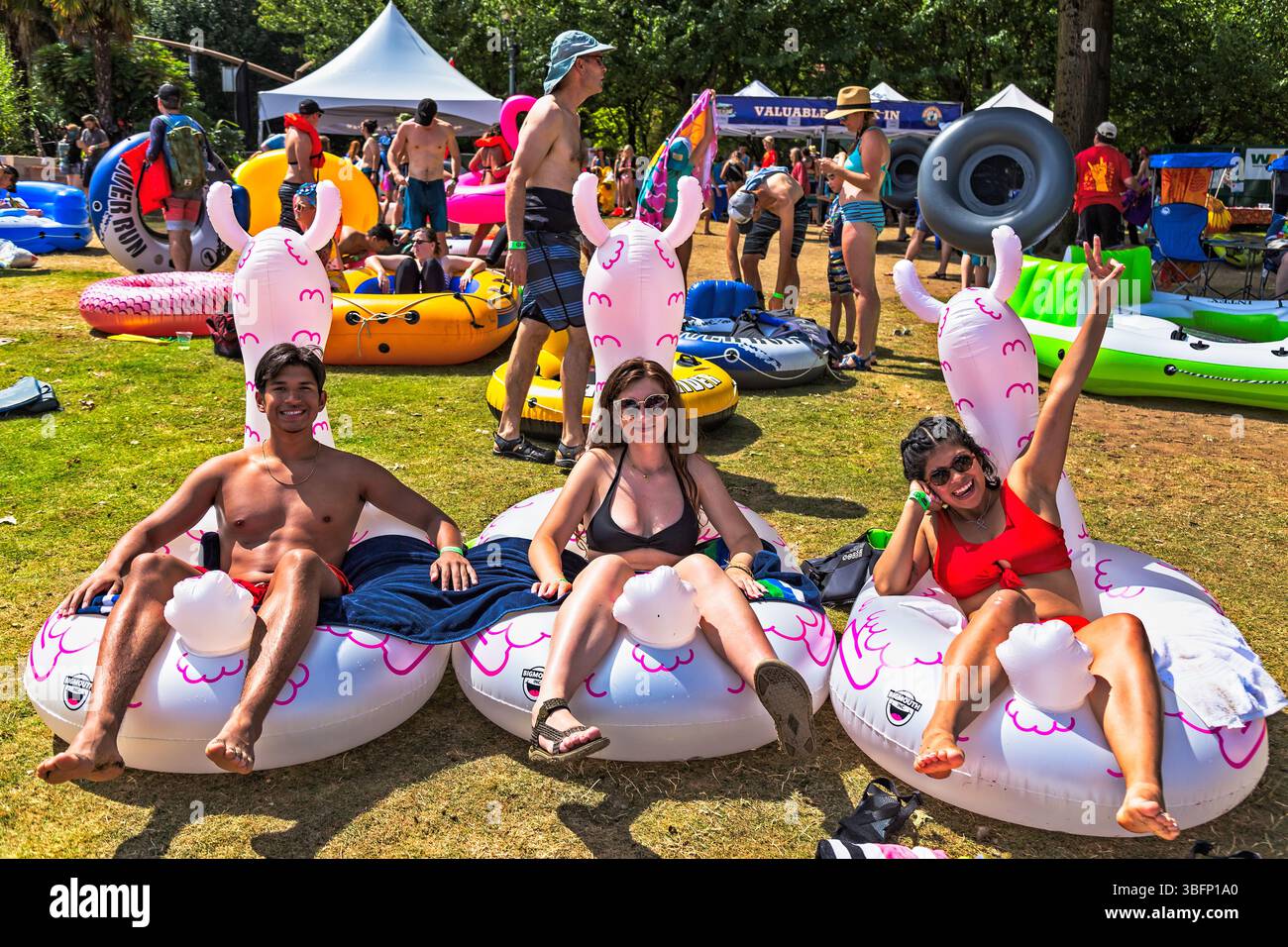 The Big Float, Portland, Oregon - July 13th 2019: People relax on inflatable llama pool floats ...