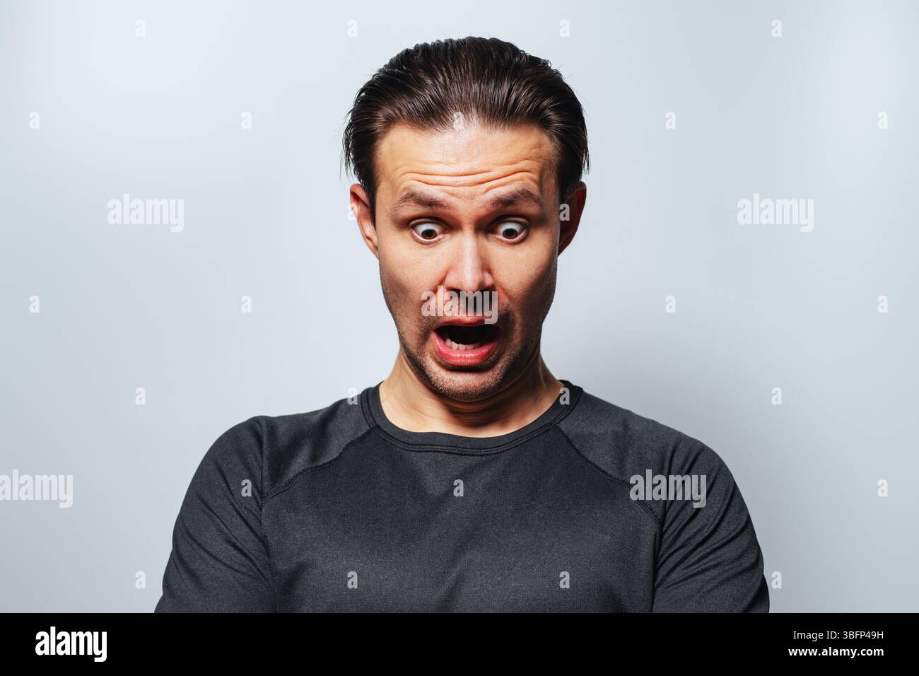 Emotional shocked man looking down portrait on white background Stock ...