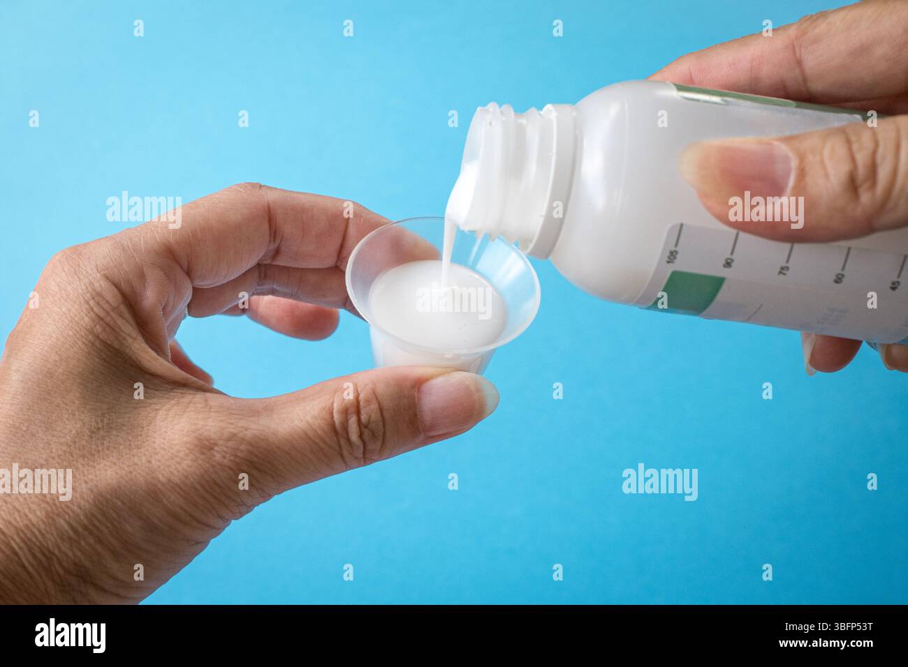 Woman pouring liquid medicine or antacid onto cup. Close up view Stock ...