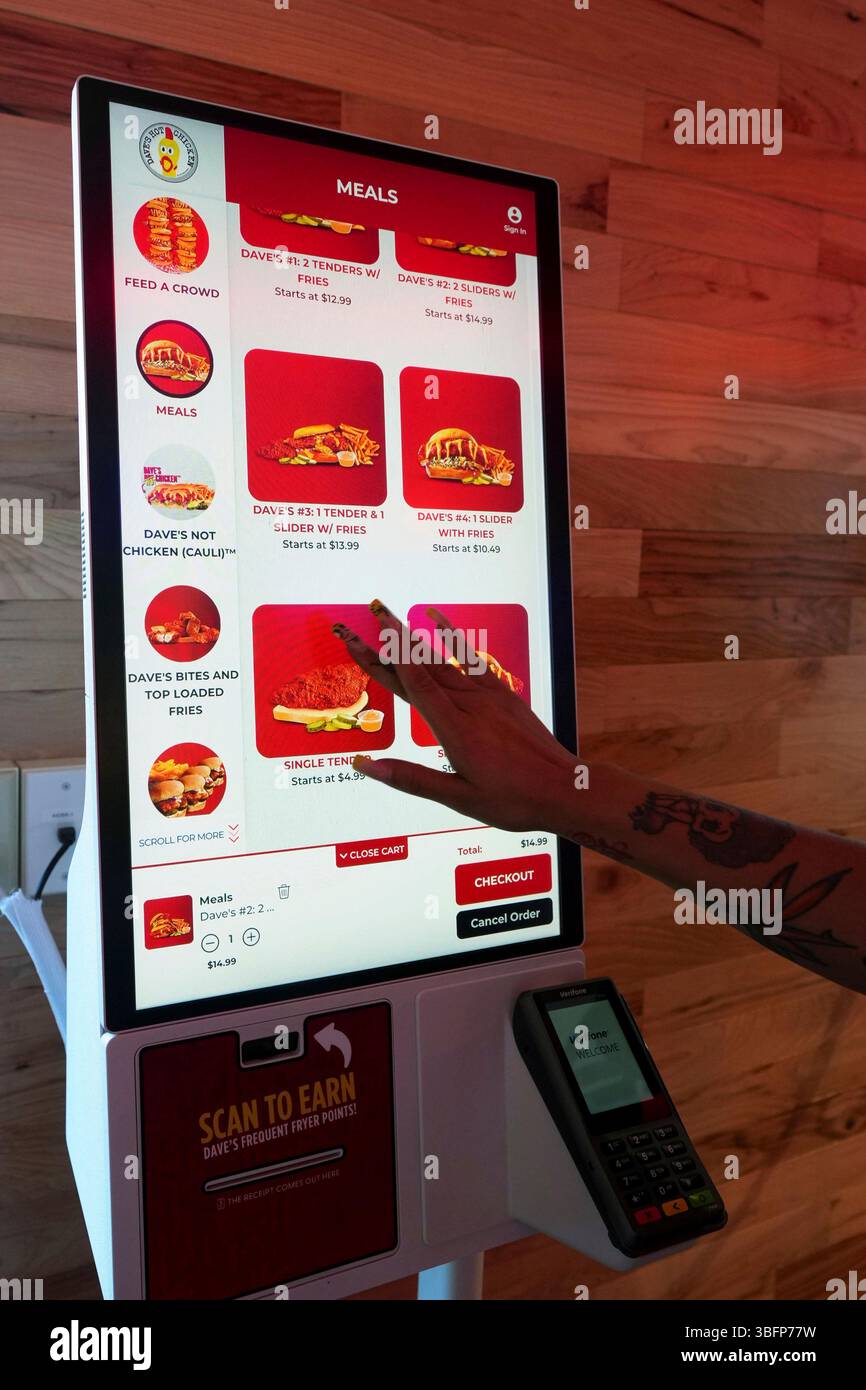 A customer uses a touch screen to order inside Dave's Hot Chicken ...