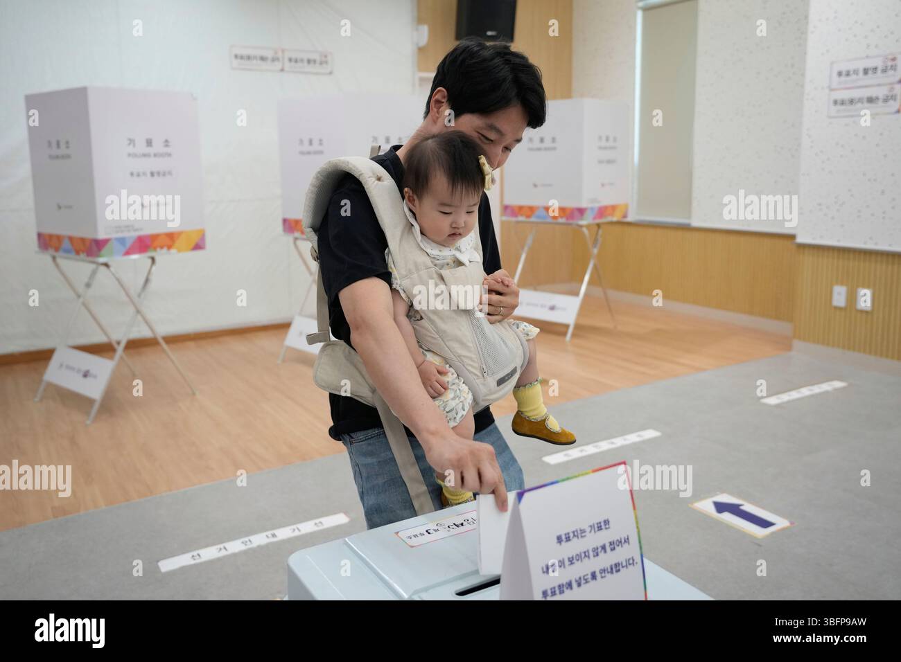 A man casts his vote with a baby for presidential election at a polling ...