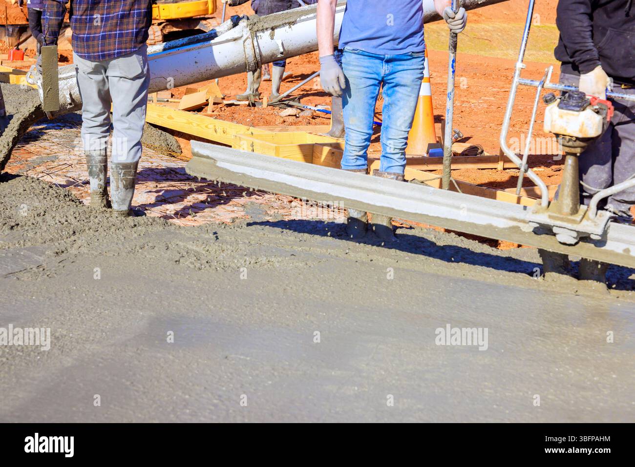 Construction workers are pouring leveling fresh concrete slab in ...